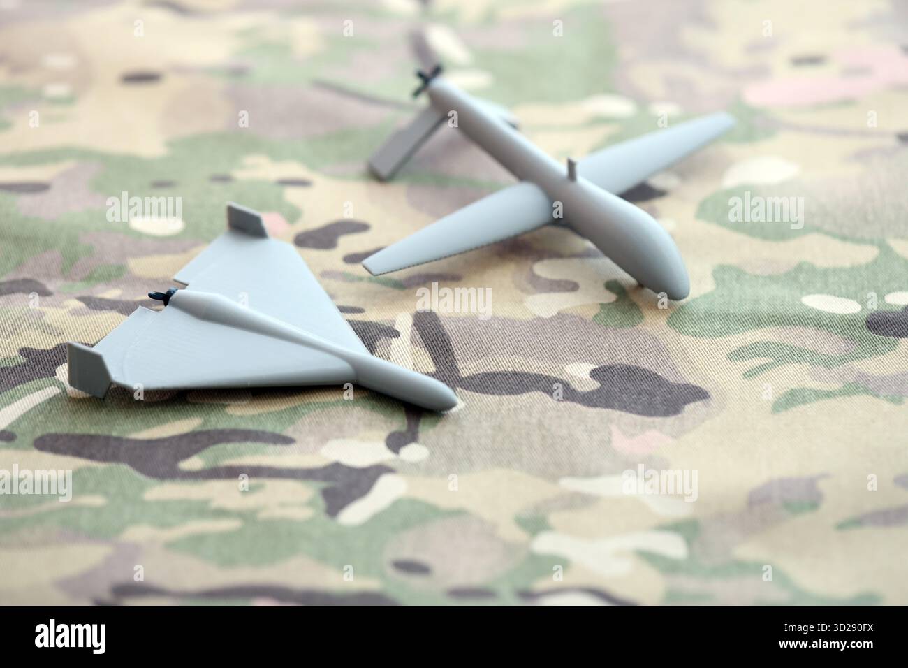 Unnamed grey toy drones models on camouflage fabric close up. Kamikaze ...