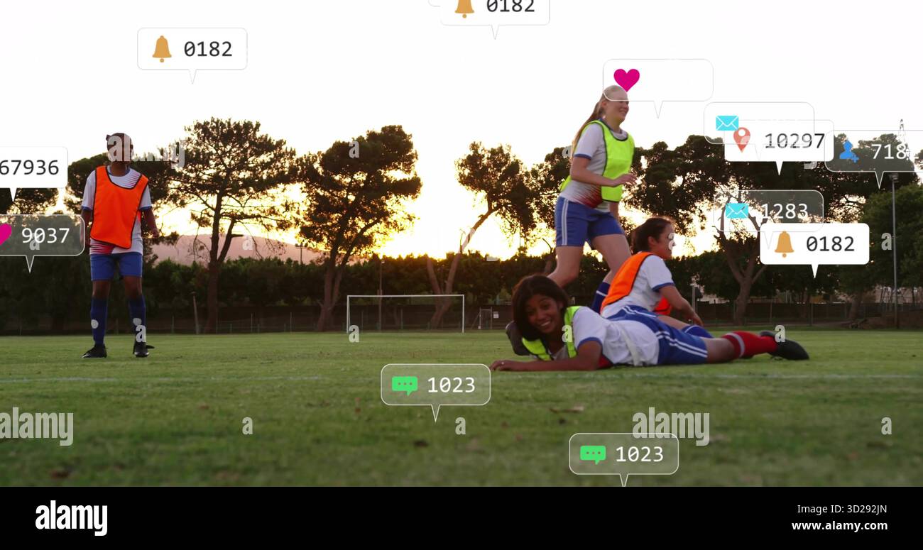 Sliding female soccer player wearing bib gliding across pitch at sunset ...