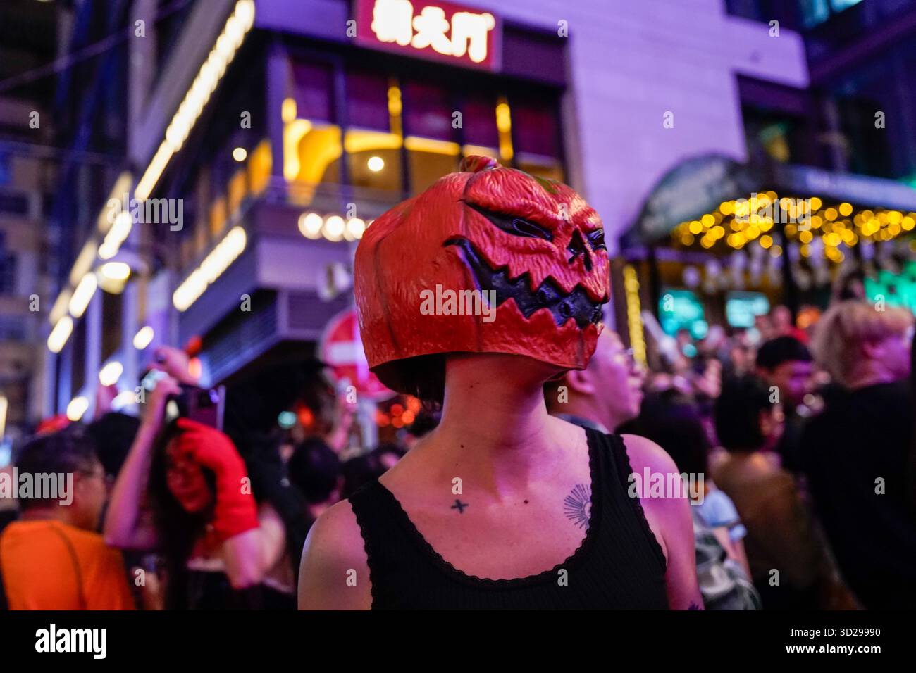 A person wearing a plastic pumpkin over their head at Lan Kwai Fong a ...