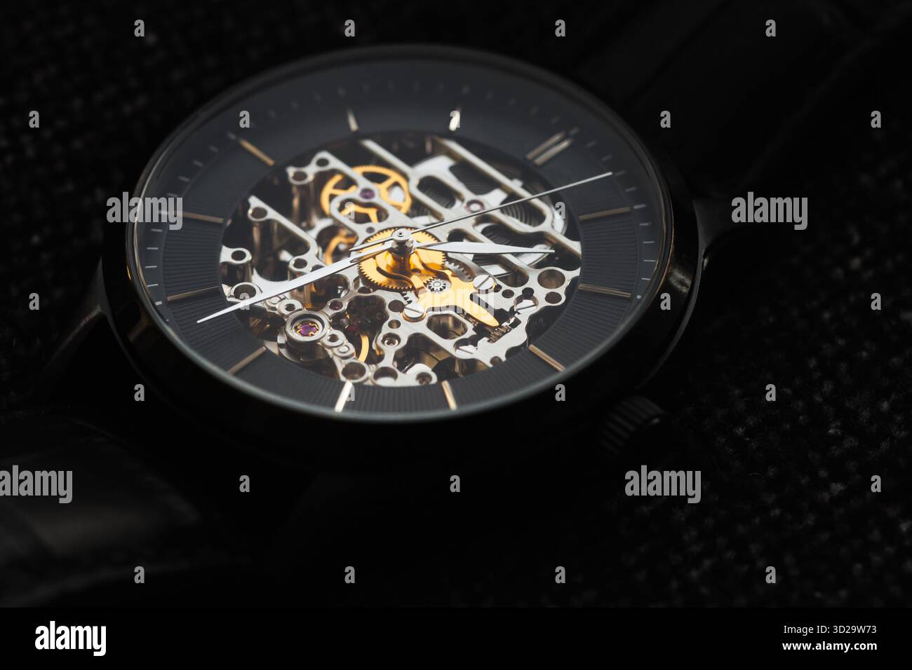 A skeleton watch with intricate gears and metallic movement inside a ...