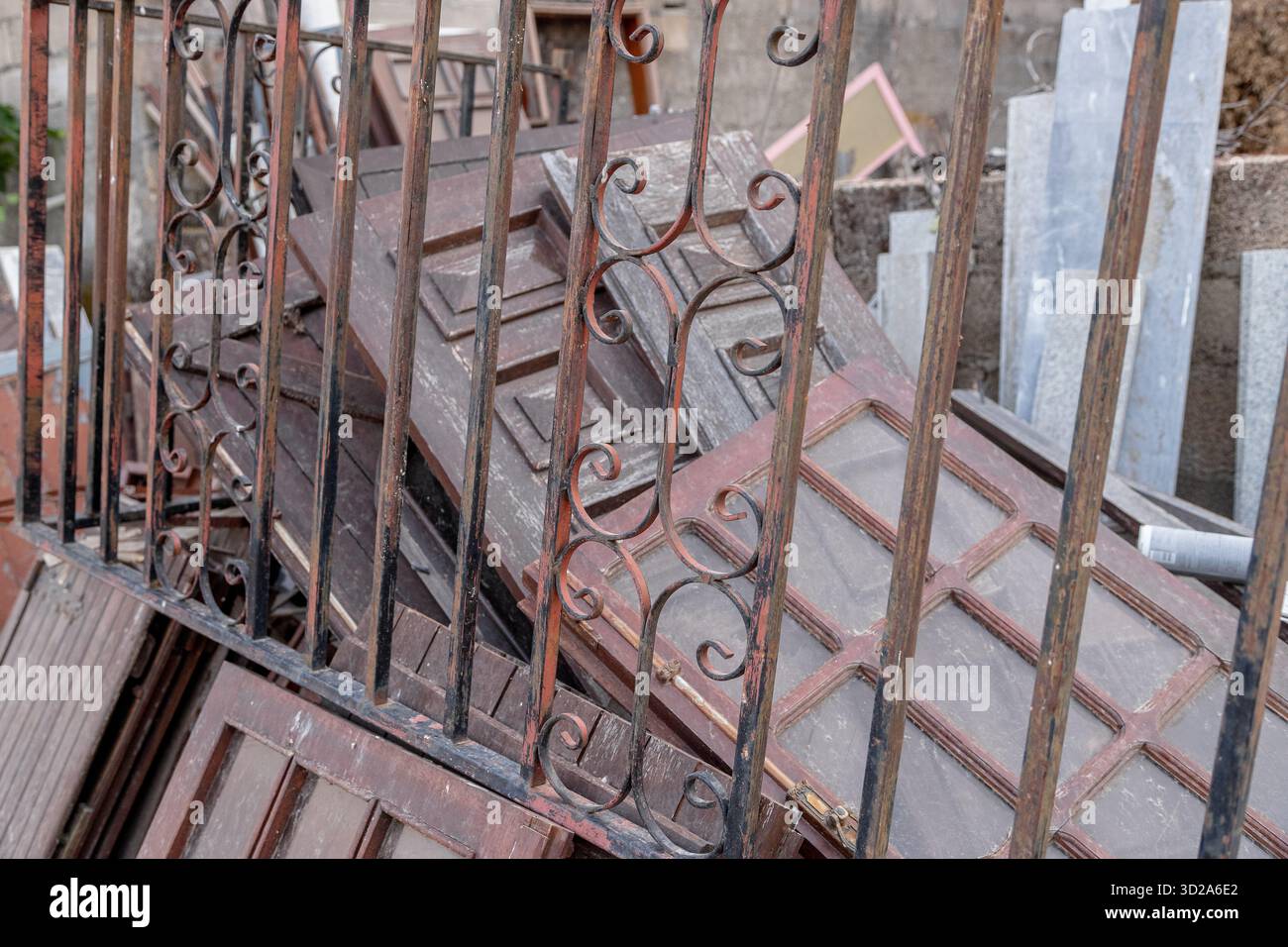 Old wooden doors and iron railings stacked in a scrap yard. Weathered ...