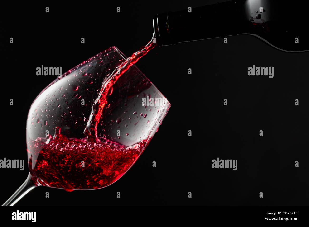 Red wine is poured into a glass. A detailed close-up shows the rapid ...