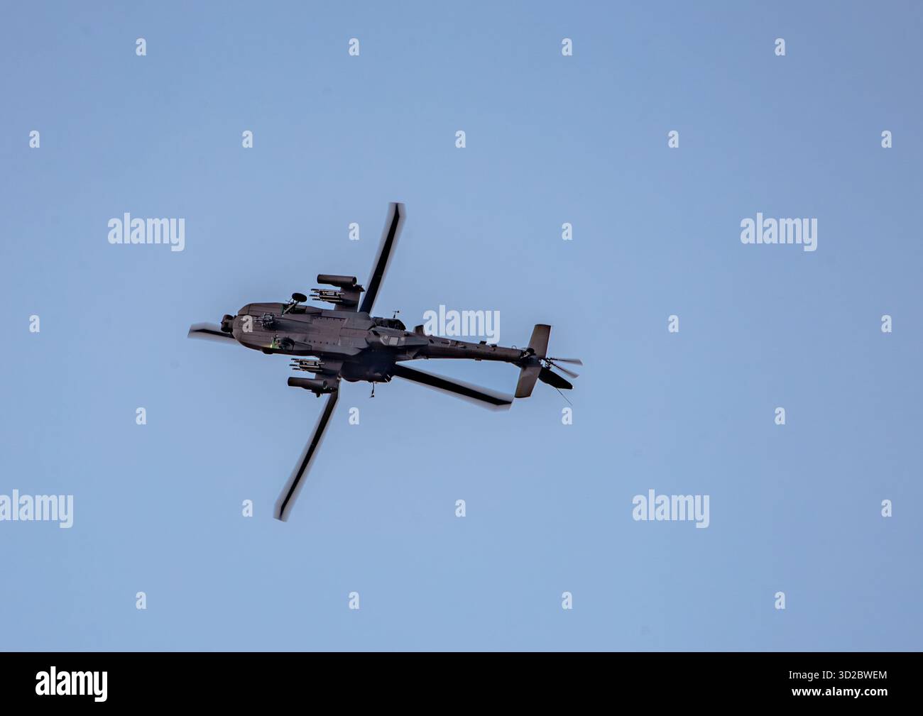 Military attack Apache helicopter flying at an angle against a clear ...