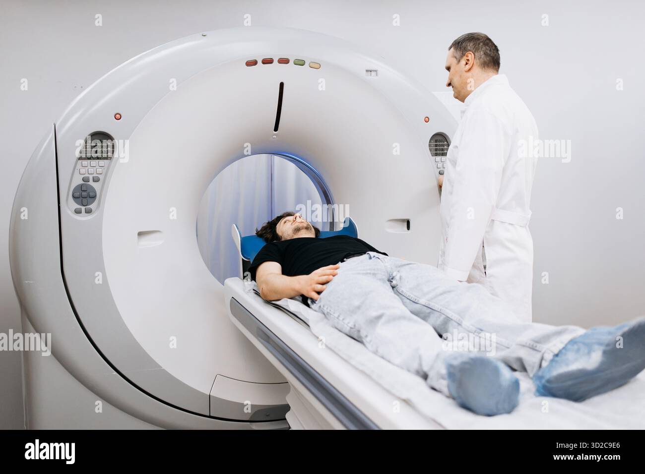Healthcare provider is preparing male patient on CT scanner bed for ...