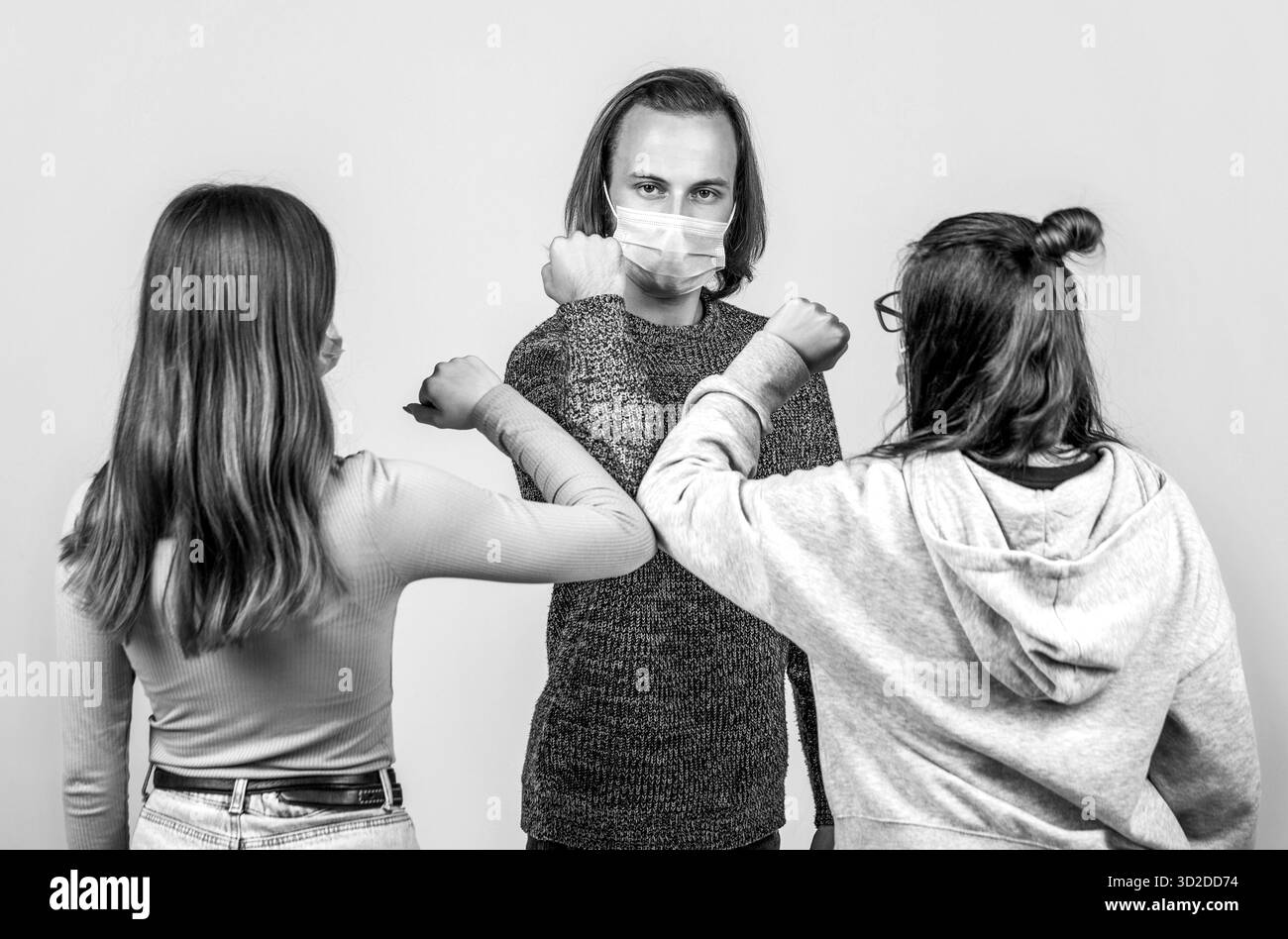 Face mask and greeting each other with the elbow. People friends bump ...