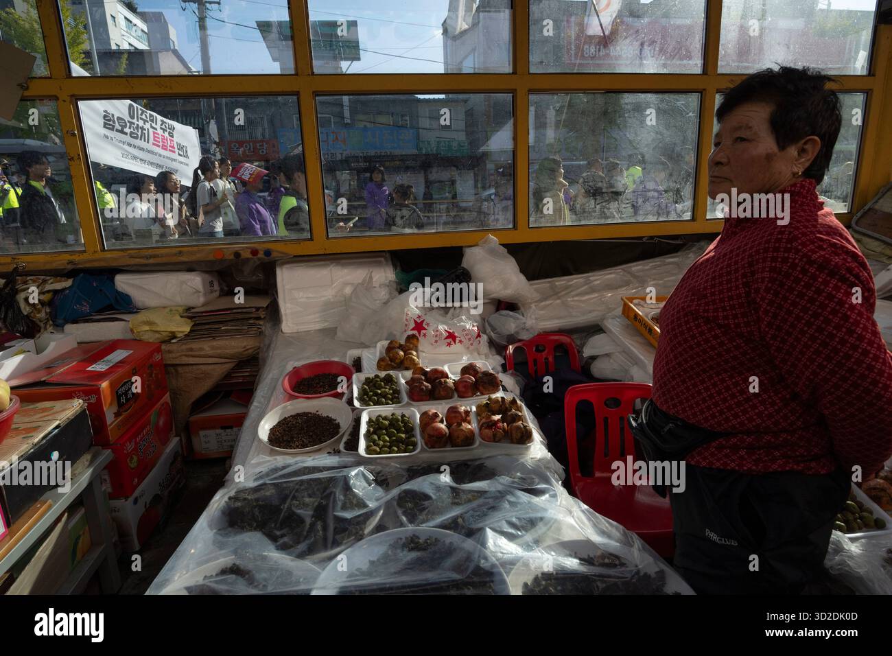 A vegetable vendor looks on as protesters march against Asia-Pacific ...