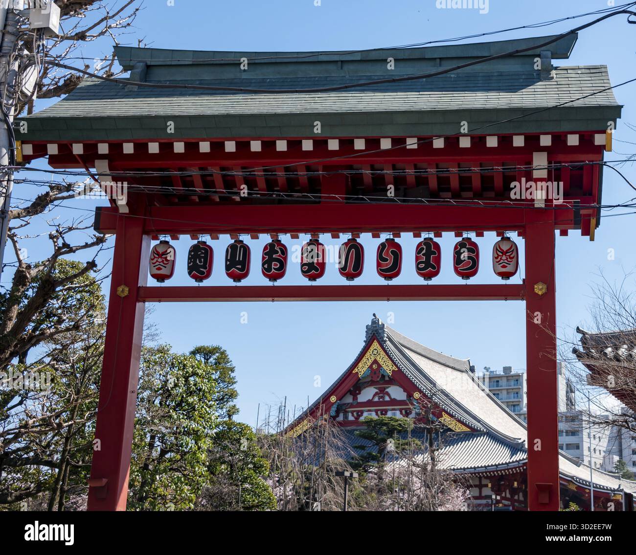 Red gate with lanterns, red and gold roof gable of a temple building ...