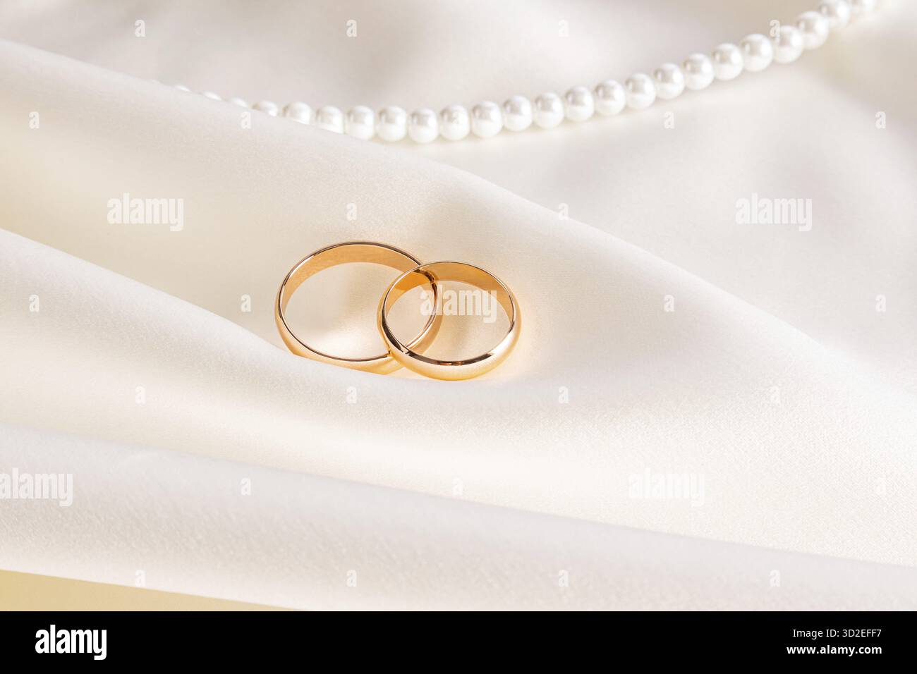 Two classic gold wedding rings on a beige satin background with ...