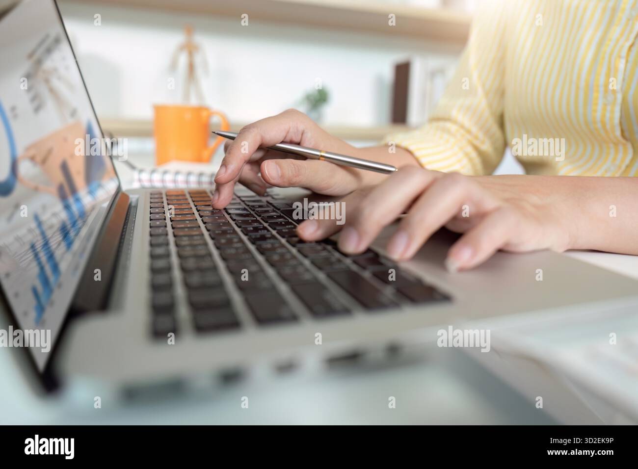 A focused individual typing on a laptop, reviewing data visualizations ...