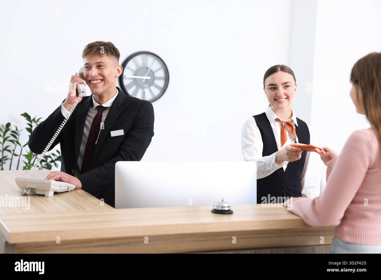 Receptionist and hostess working with guest at reception desk indoors ...