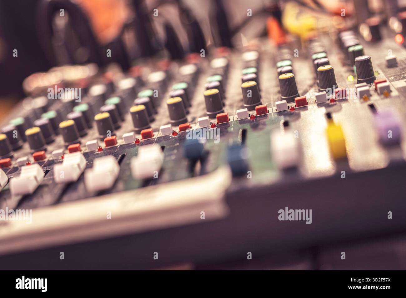 Mixing console showing various knobs, faders, and buttons, representing ...