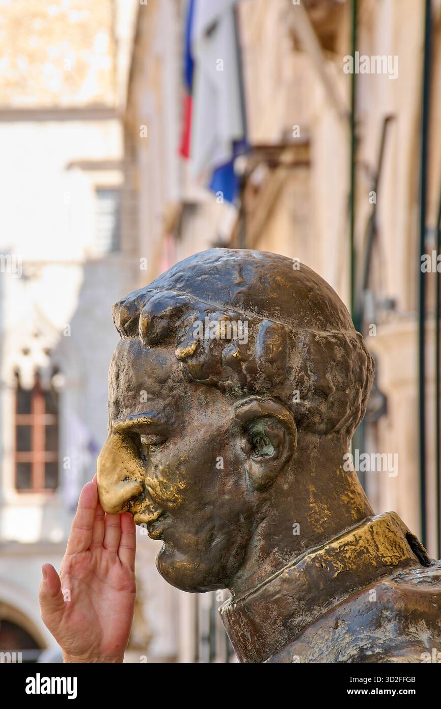 Close-up of a tourist's hand rubbing the golden nose of the Marin Drzic ...