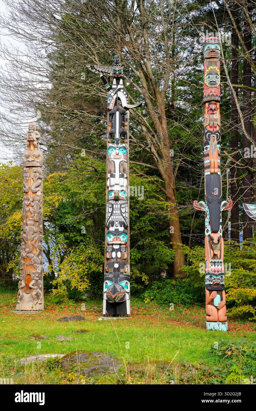 A row of three Indigenous totem poles rises in Stanley Park, featuring ...