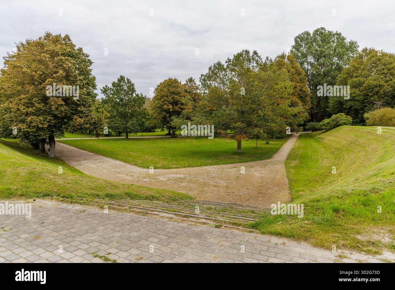 A wide view of a central grassy meadow in a park, where two gravel ...