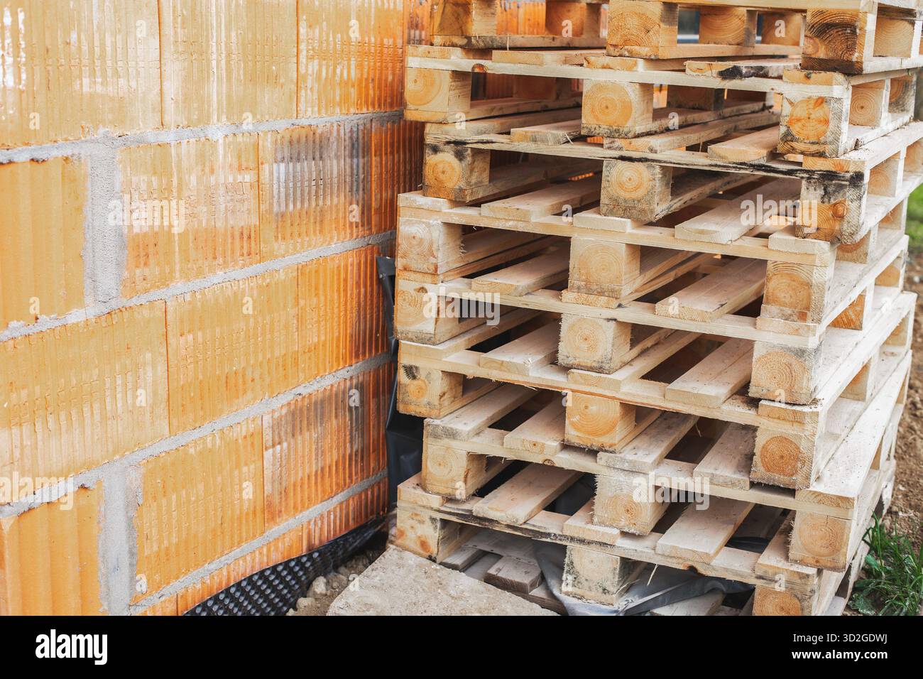 Wooden pallets stacked under unfinished brick wall at a construction ...