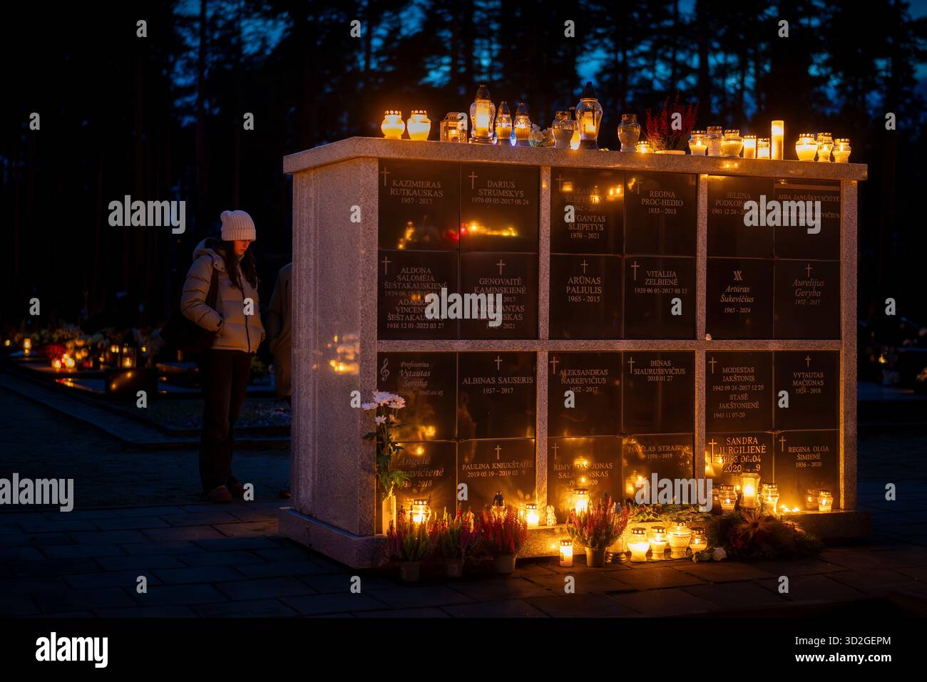 A woman lights a candle at a grave during All Saints Day, a Catholic ...