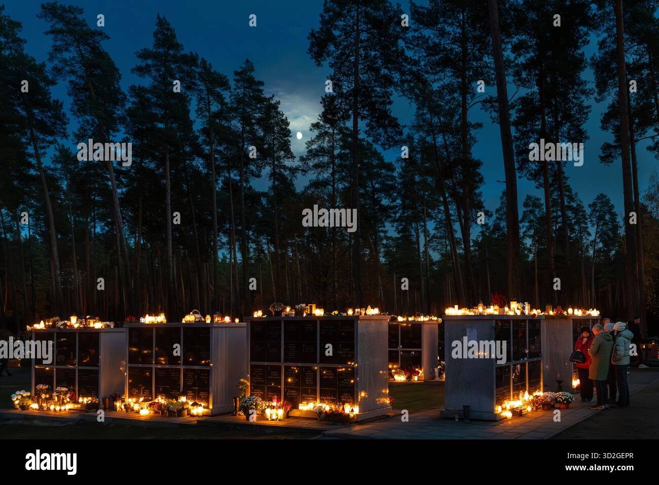 People light candles at a grave during All Saints Day, at the cemetery ...