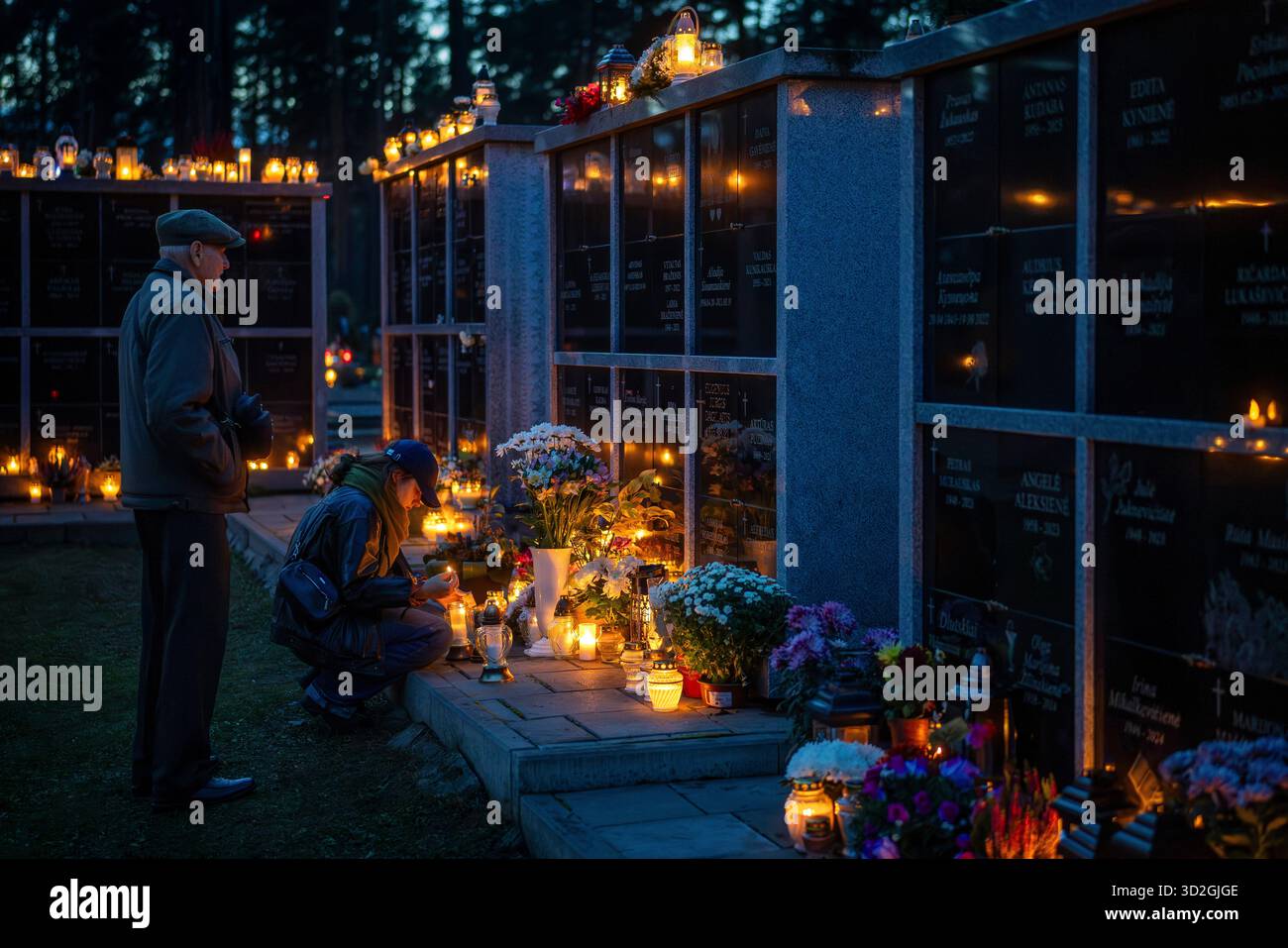 People light candles at a grave during All Saints Day, at the cemetery ...