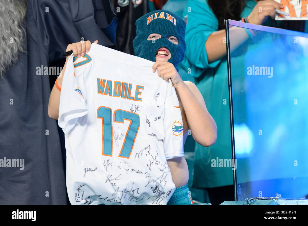 A young Miami Dolphins fan holds up an autographed Jaylen Waddle jersey ...