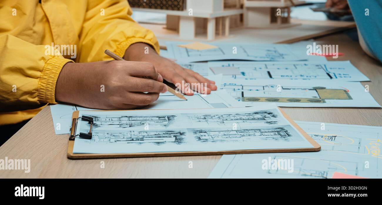 An architect focused on sketching detailed designs and plans at a work ...