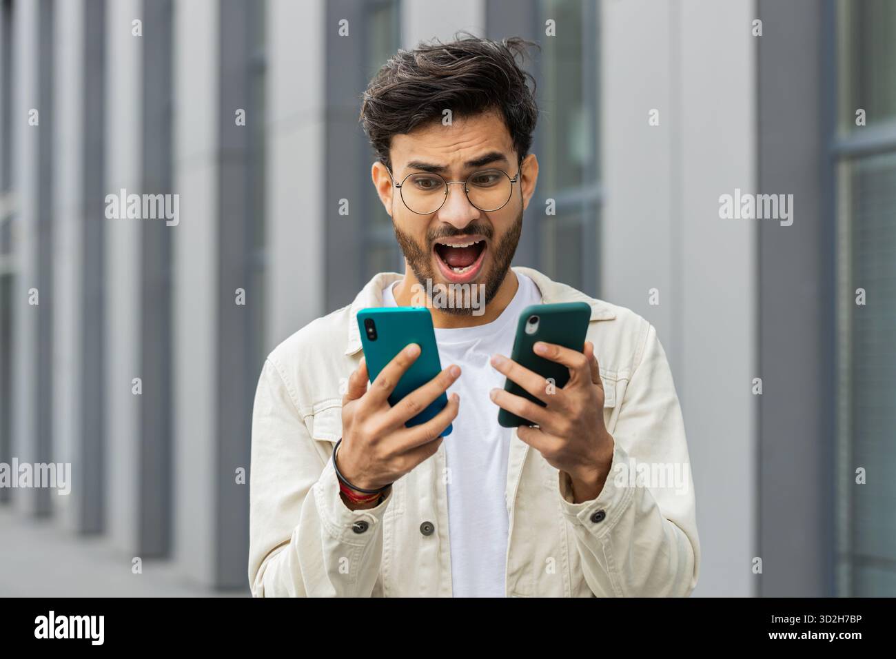 Irritated nervous stressed Indian man talking screaming on two mobile ...