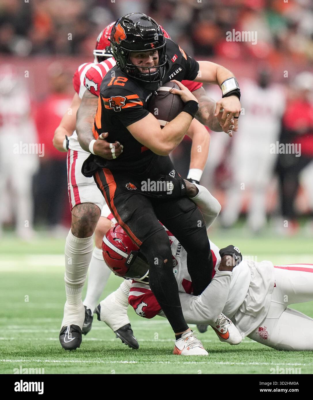 B.C. Lions quarterback Nathan Rourke, front, is tackled by Calgary ...