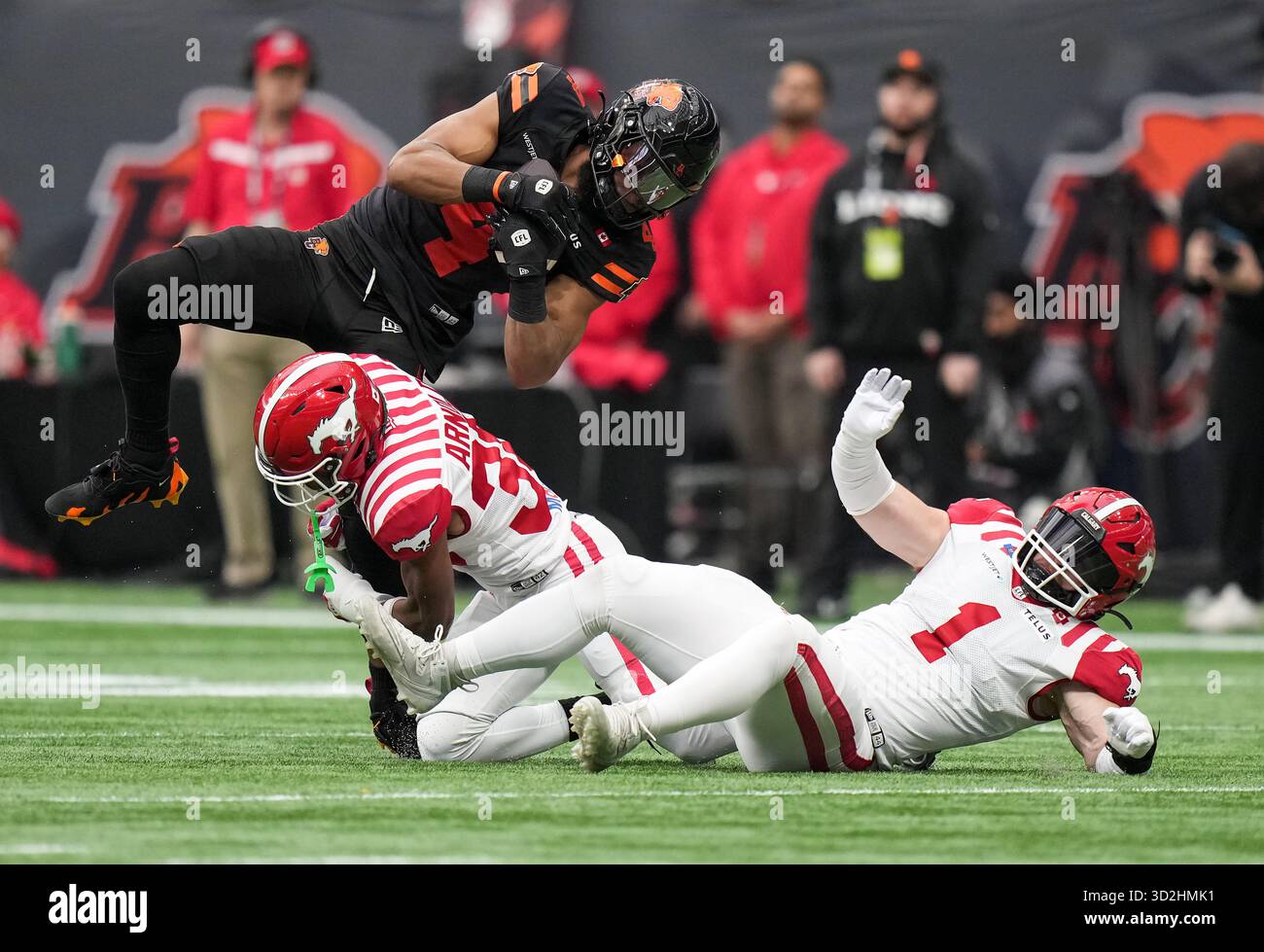 B.C. Lions' Keon Hatcher, back left, is tackled by Calgary Stampeders ...