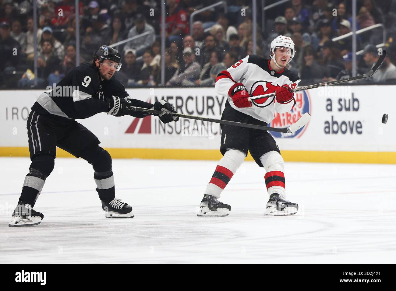 New Jersey Devils defenseman Luke Hughes, right, passes the puck ...