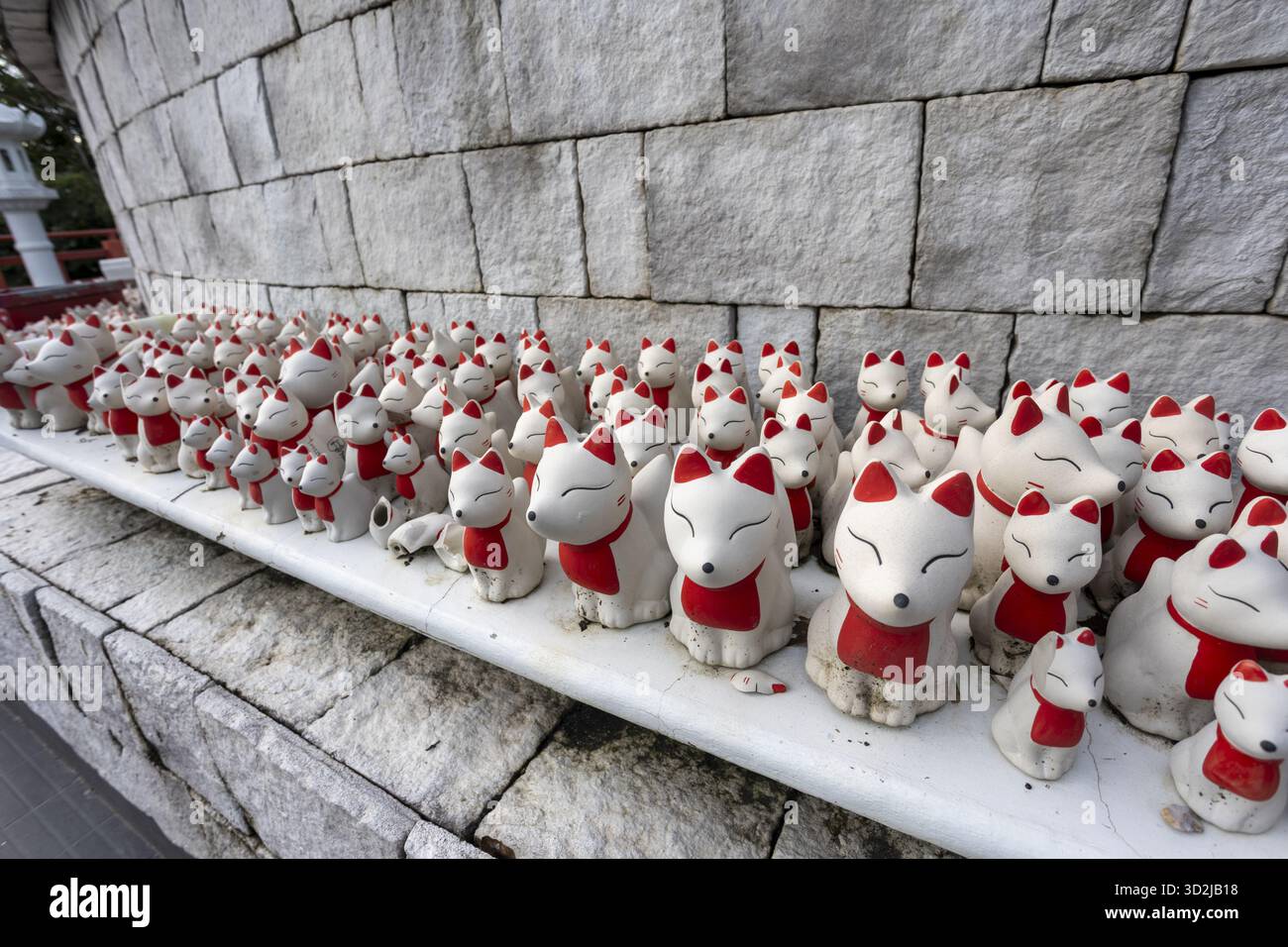 Large group of small, white ceramic fox statues with red scarves stands ...