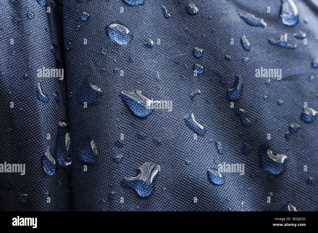 Close up detail of waterproof blue fabric with water droplet beading on ...
