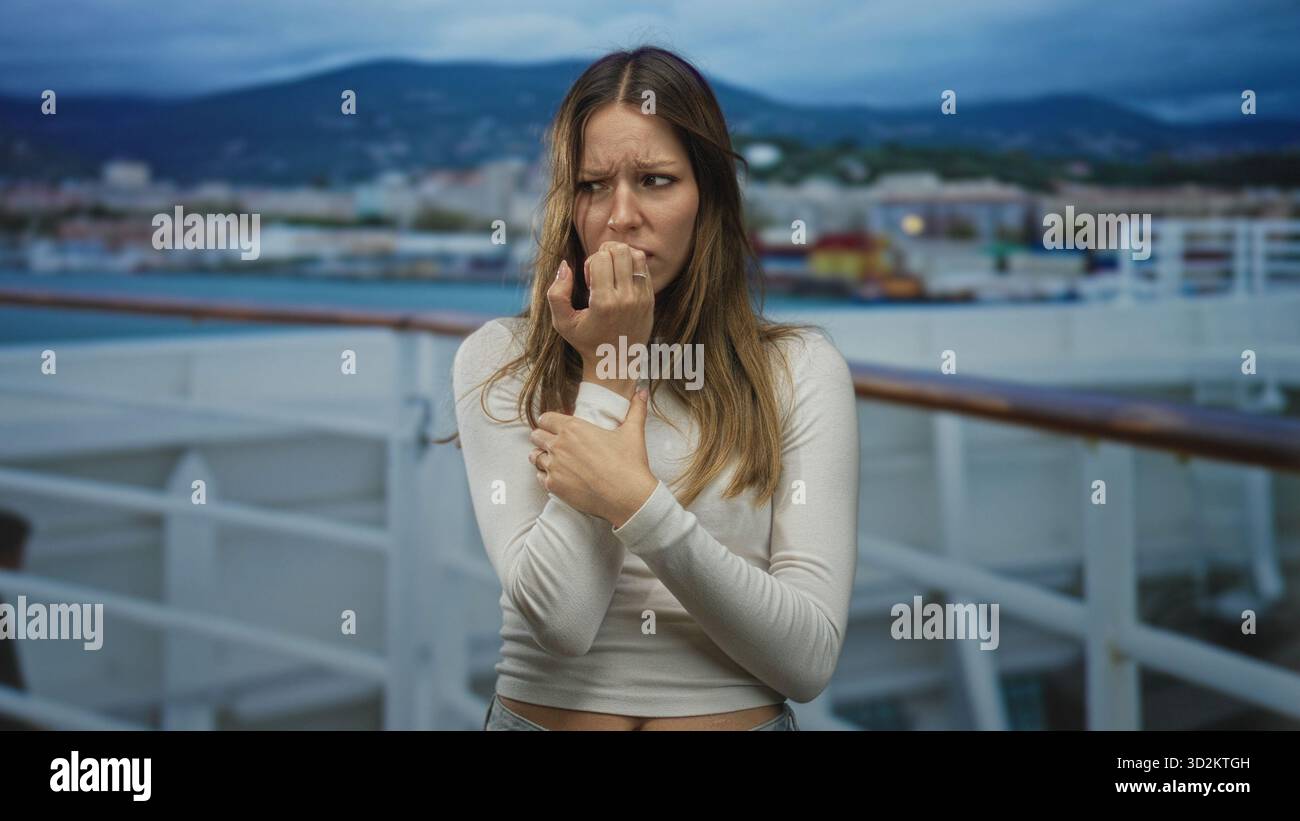 Woman biting fingernails with fingers and hand on chest on cruise ship ...