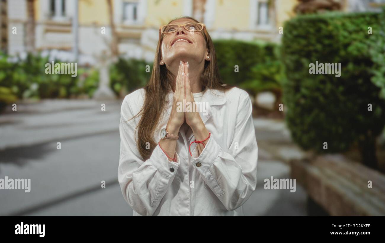 Woman scientist in white lab coat, hands pressed together in prayer ...