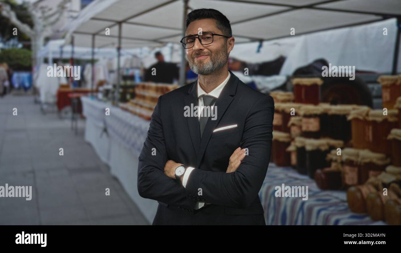 Man in suit and tie with glasses and beard, arms crossed showing hands ...