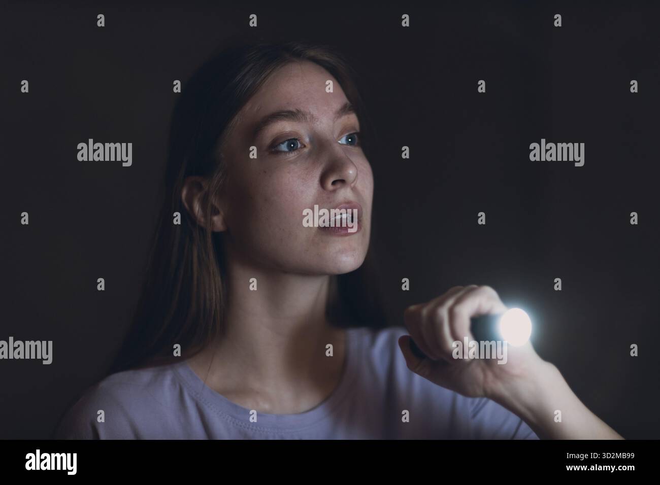 Woman scared holding hand flashlight in darkness and afraid of violence ...