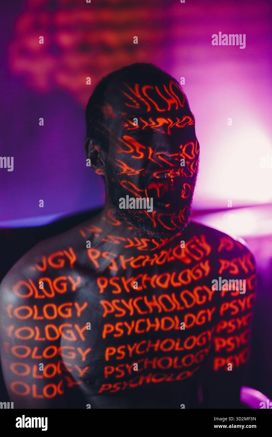 Young adult man with word Psychology on his face shout in the dark ...