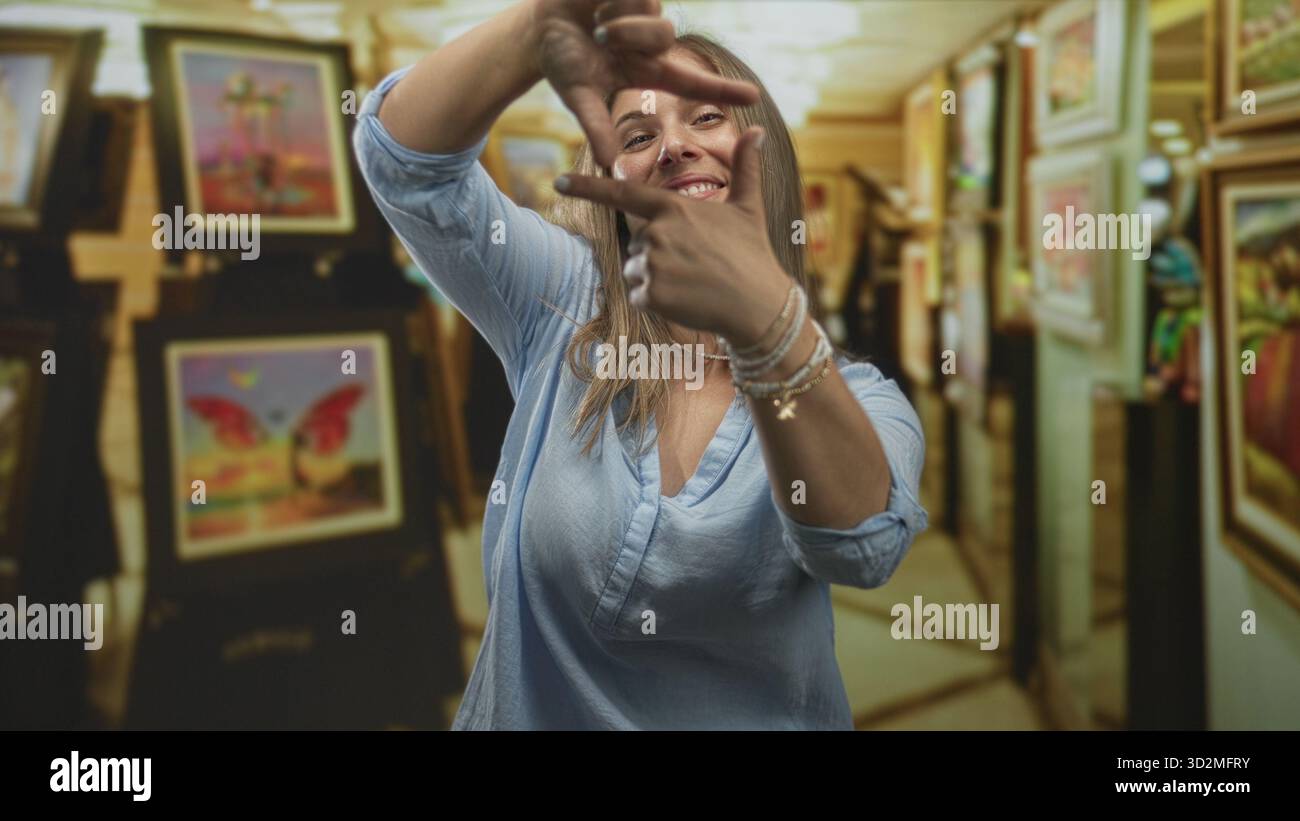 Young woman frames painting exhibit with hands forming rectangle in art ...