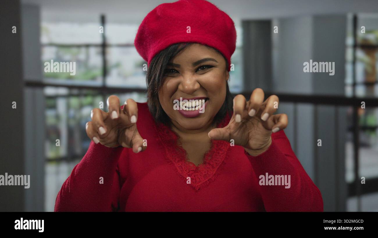 Woman wearing red beret and sweater posing playfully in a hotel lobby ...