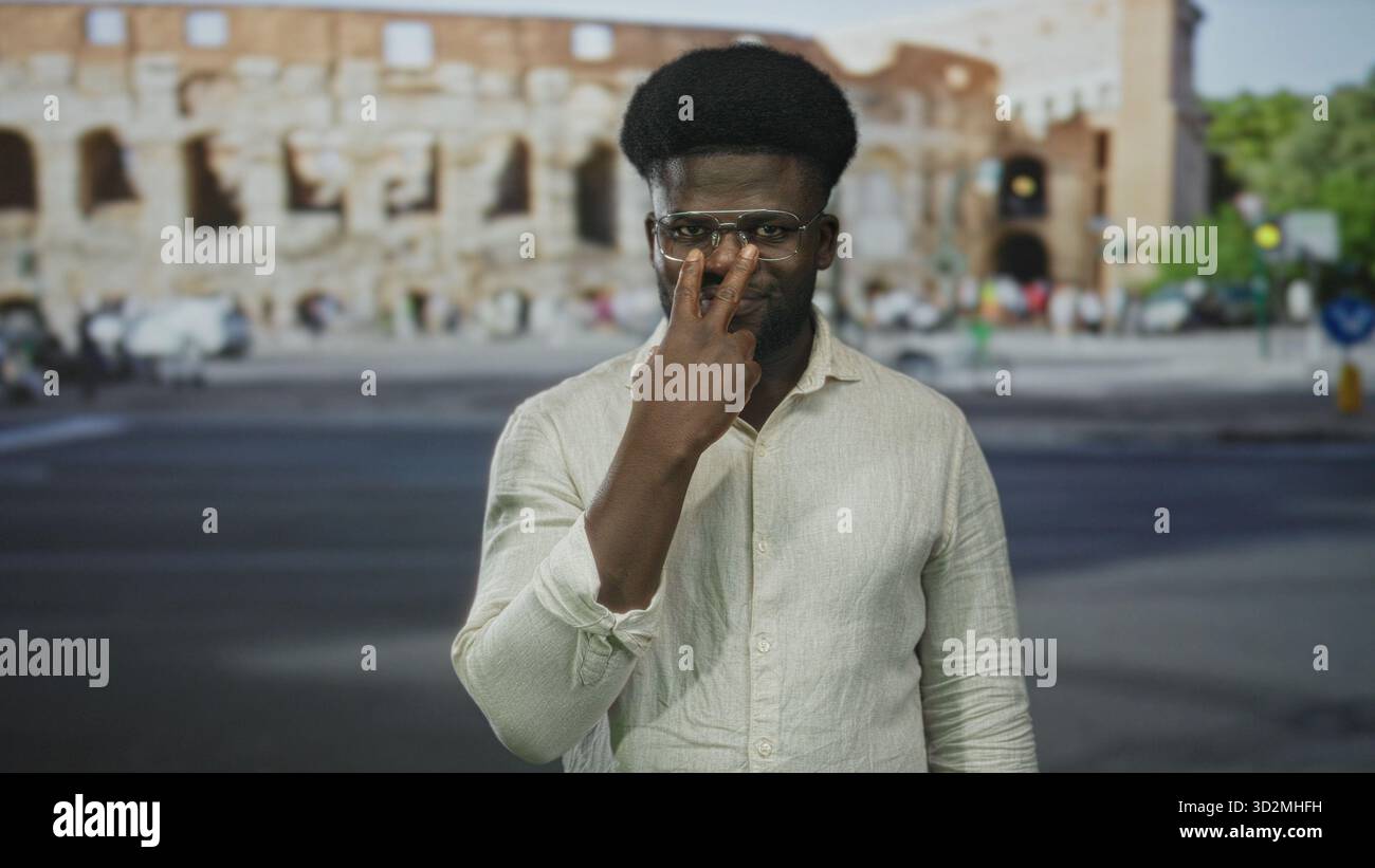 Man making peace sign with hand and pointing toward camera, wearing ...