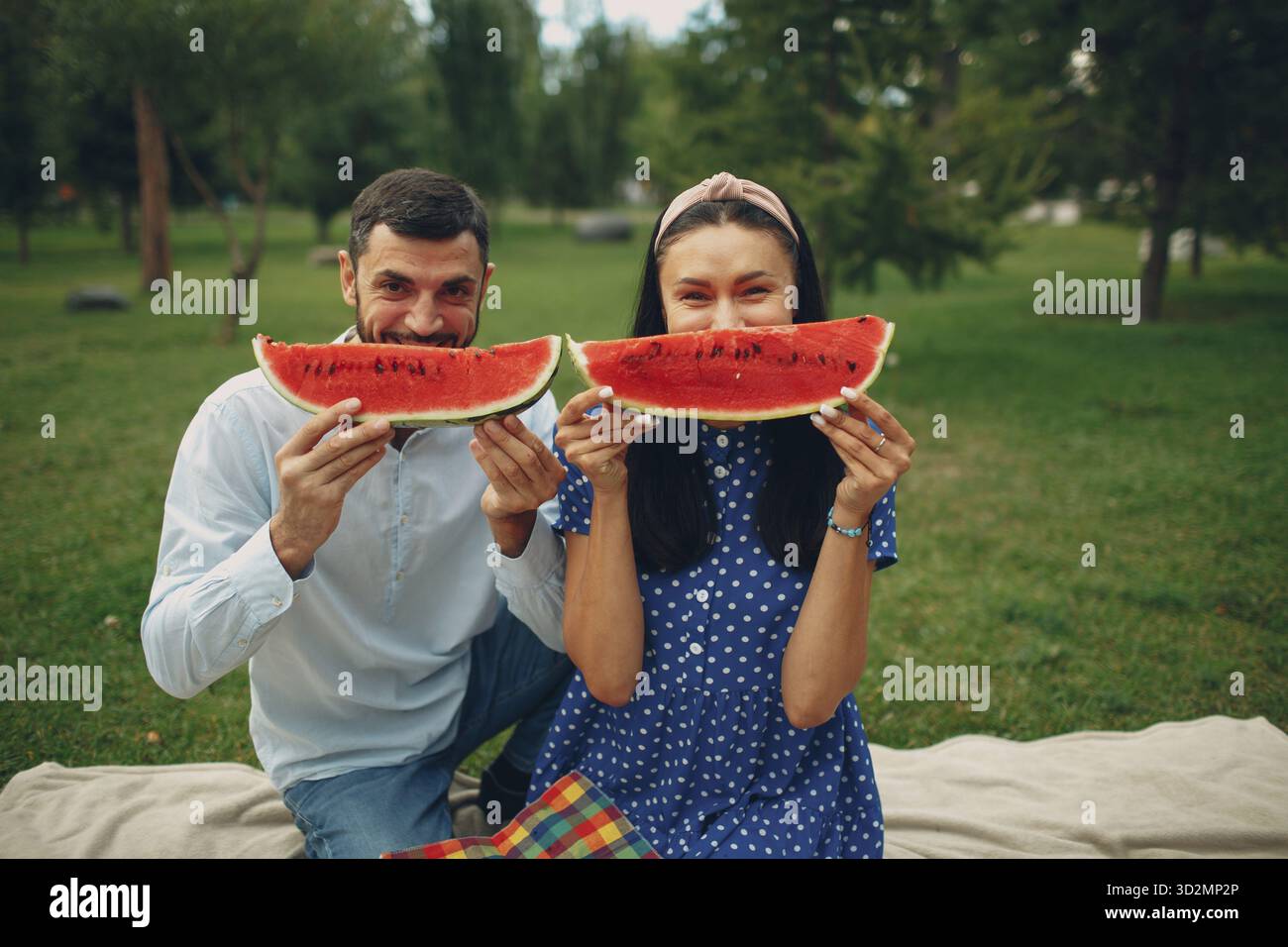 Young adult woman and man couple picnic at green grass meadow in park ...