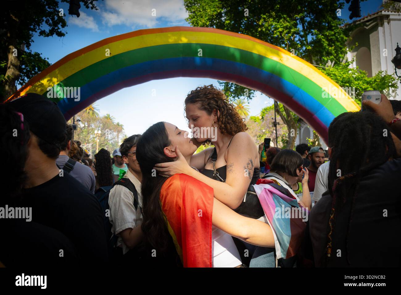 A female couple kisses in a show of pride and love under the rainbow ...