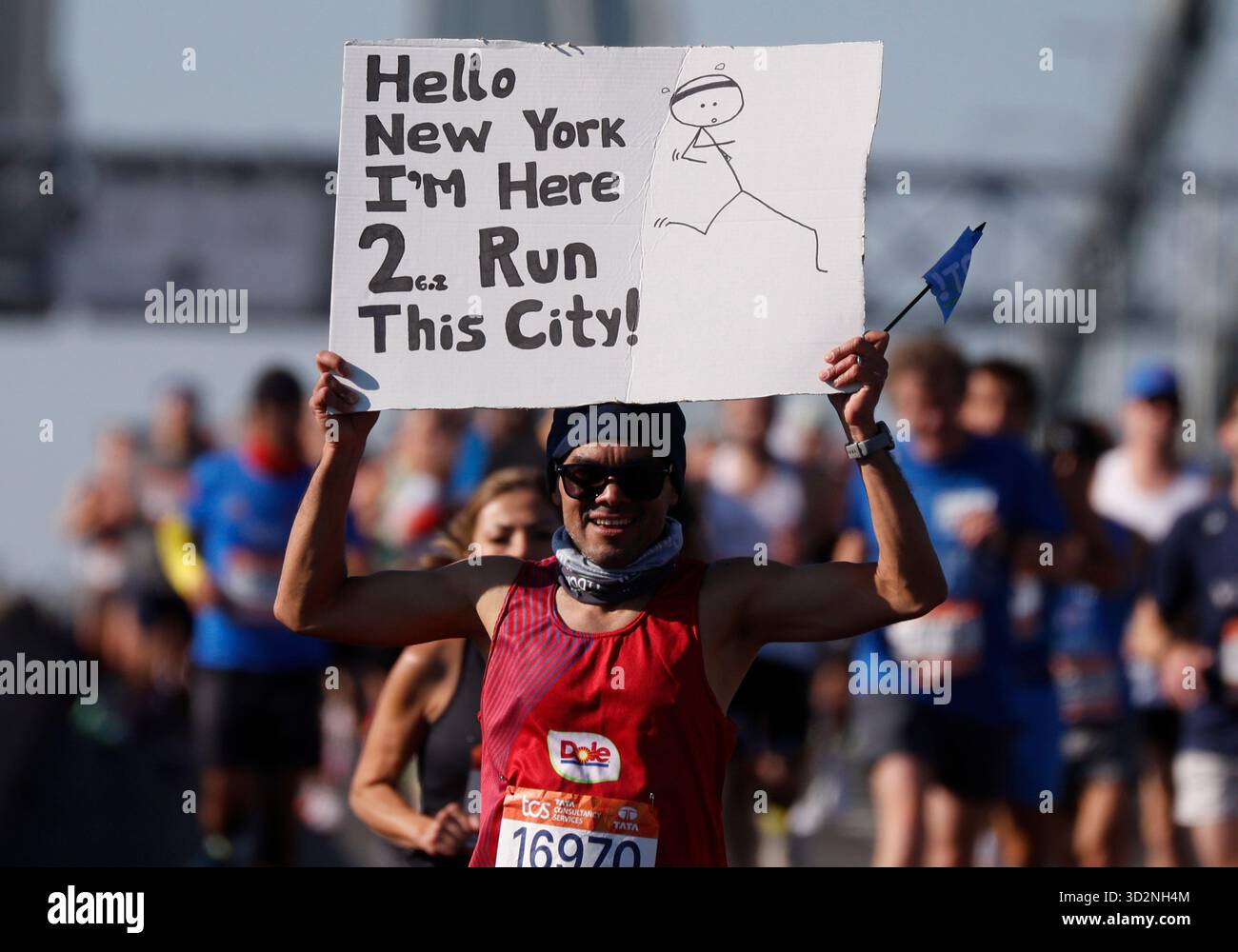 A runner holds a sign while crossing over the span of Verrazzano ...