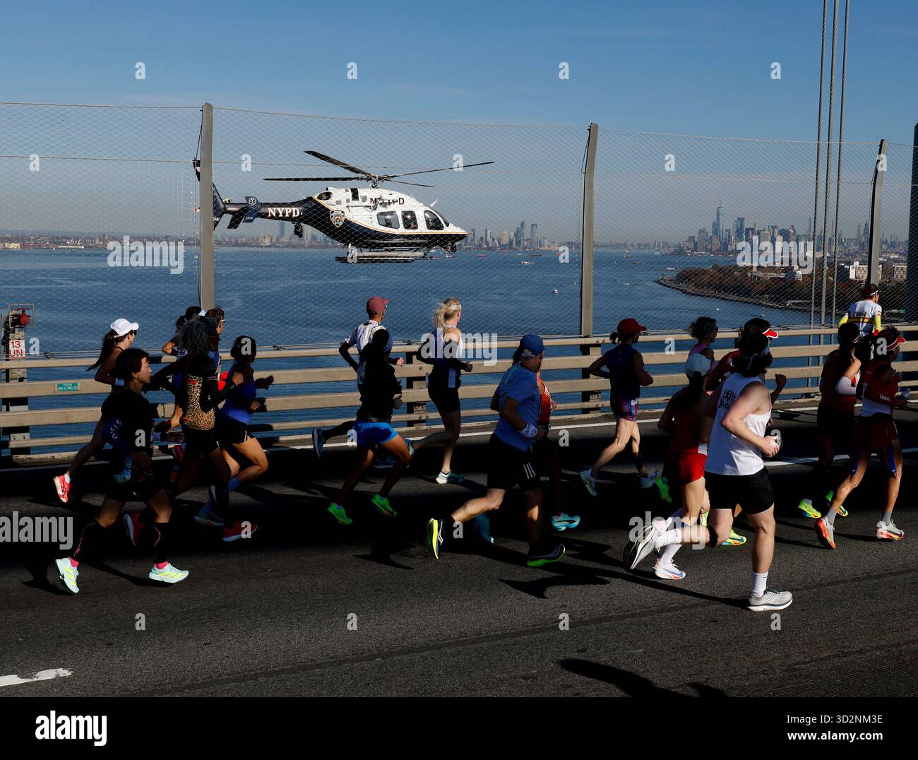An NYPD police helicopter flies by as runners cross over the span of ...