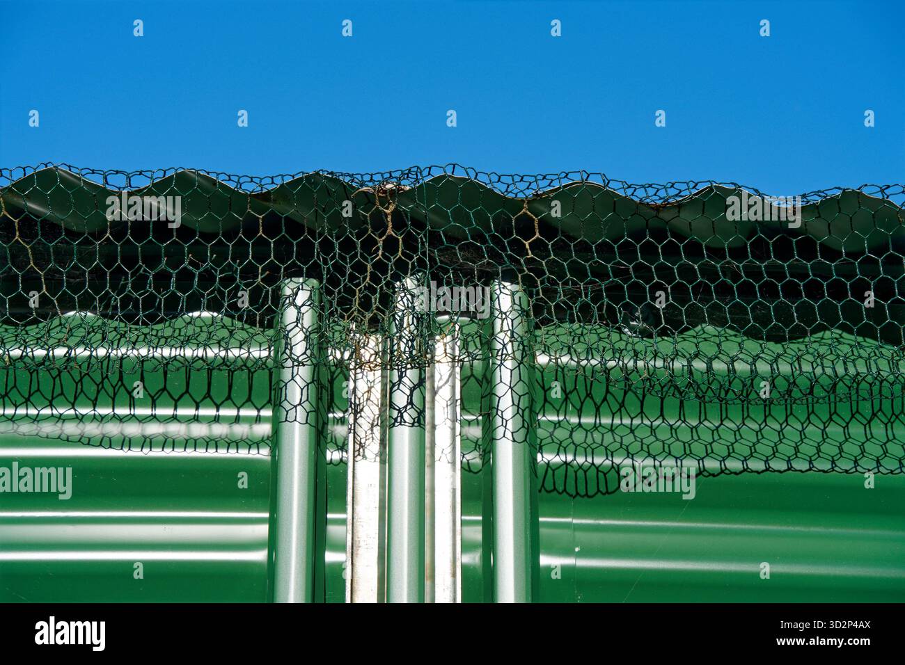 A green corrugated iron water tank with wire netting to keep animals ...