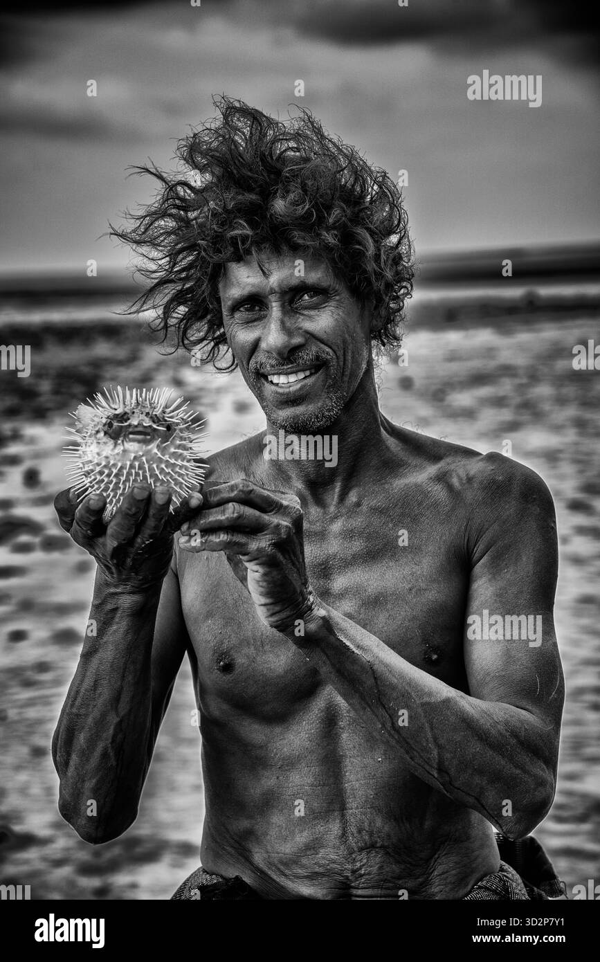 A cave man proudly displays a pufferfish at Detwah lagoon in Socotra ...