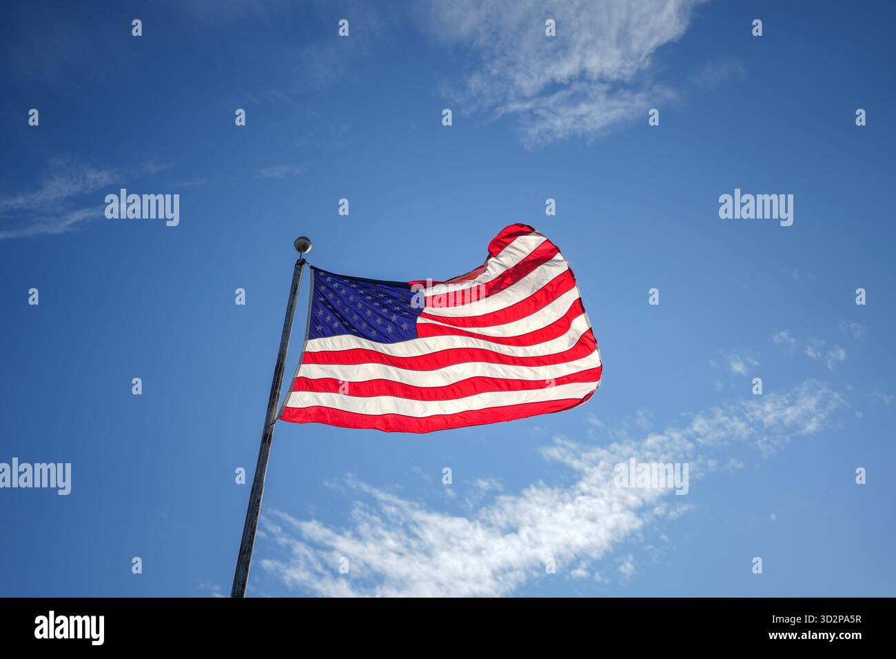 American flag waving proudly against a vivid blue sky—symbolizing ...