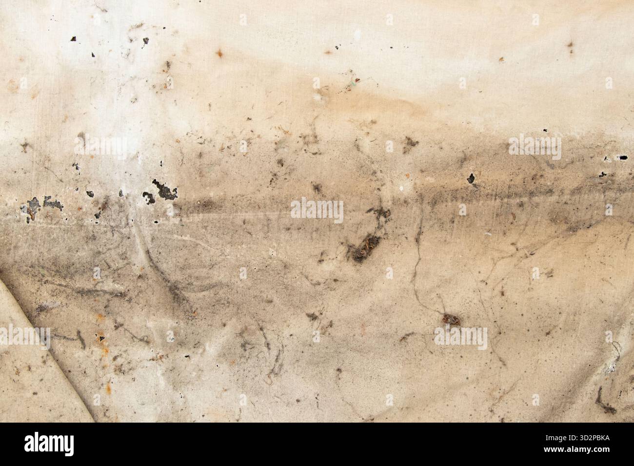 A close-up of an old, faded, light-colored fabric with dirt and signs ...