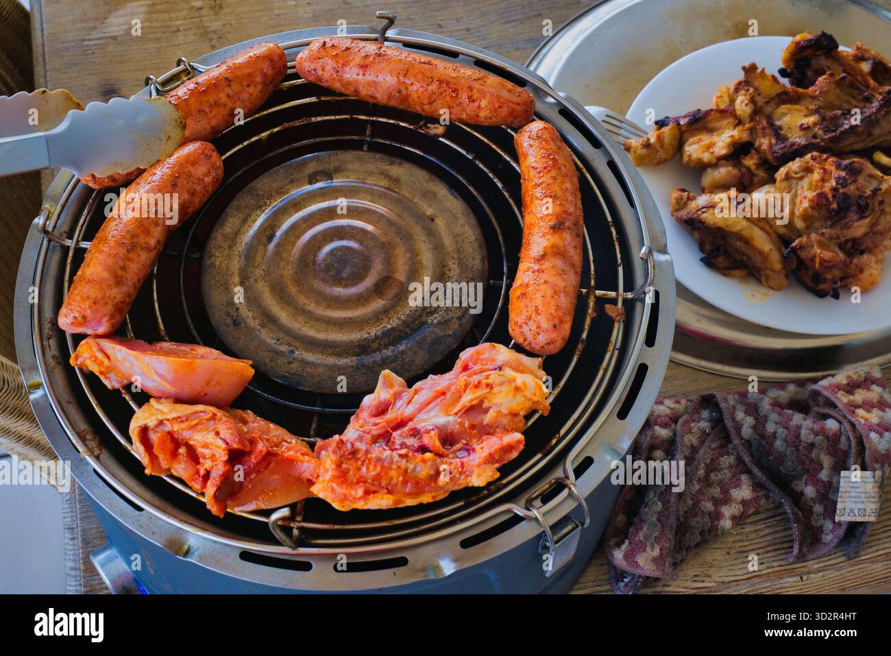 Outdoor grill with sausages and seasoned pork cooking at home barbecue ...