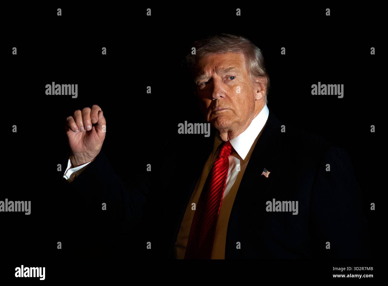 President Donald Trump is illuminated by a camera flash as he gestures ...
