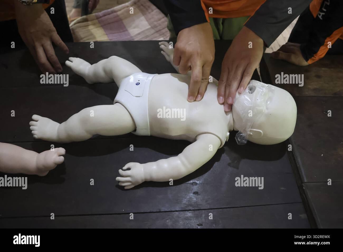 First aid training baby CPR dummy, with instructor demonstrating chest compressions. This scene ...