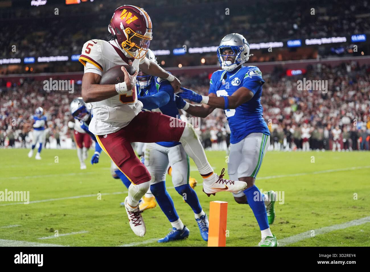 Washington Commanders quarterback Jayden Daniels (5) is shoved out of ...